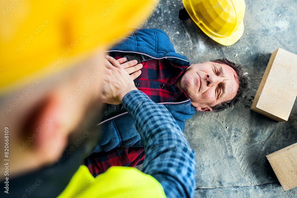 Colleague performing CPR on an injured worker lying on the ground after ...