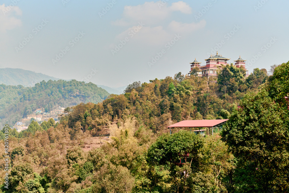 Tibetan temple on mountain shrouded in green vegetation amidst peaceful ...