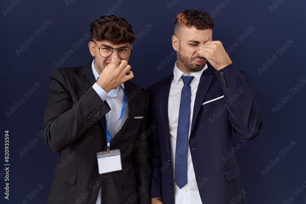 Two hispanic business men wearing business clothes smelling something ...
