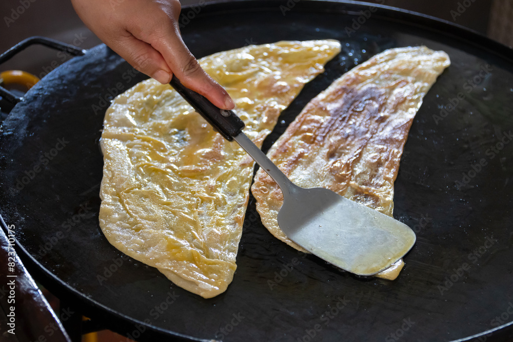 Cooking roti, a type of flatbread. The roti is being cooked on a large ...
