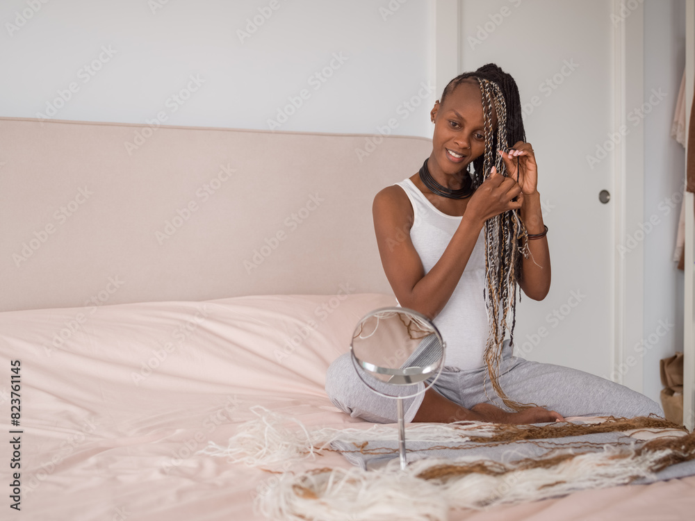 Excited Black woman braiding hair and looking in the mirror Stock Photo ...