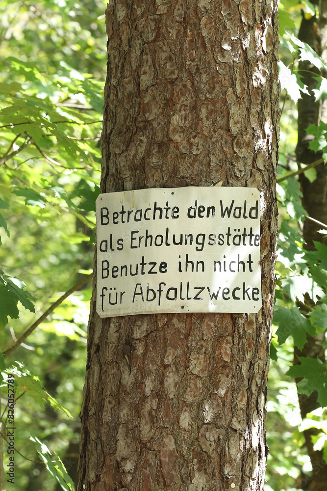 Schild an einem Baum: Betrachte den Wald als Erholungsort. Benutze ihn ...