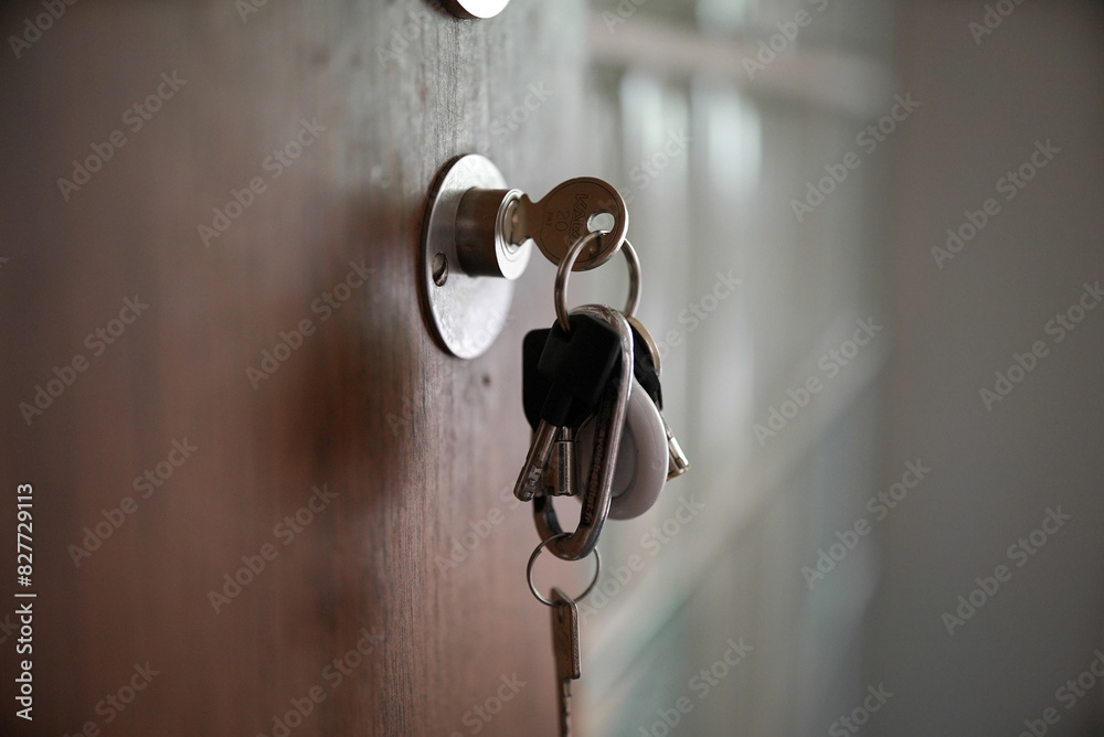 Keys hanging from a keyhole in a wooden door. This close-up shot ...