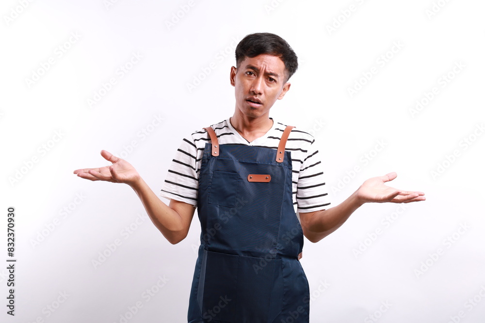 Confused and pissed-off young asian male in apron shrugging with hands ...