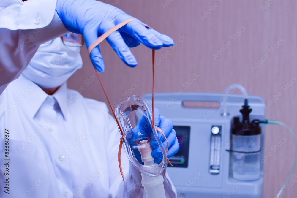 Hands in medical gloves hold out an oxygen mask against the background ...