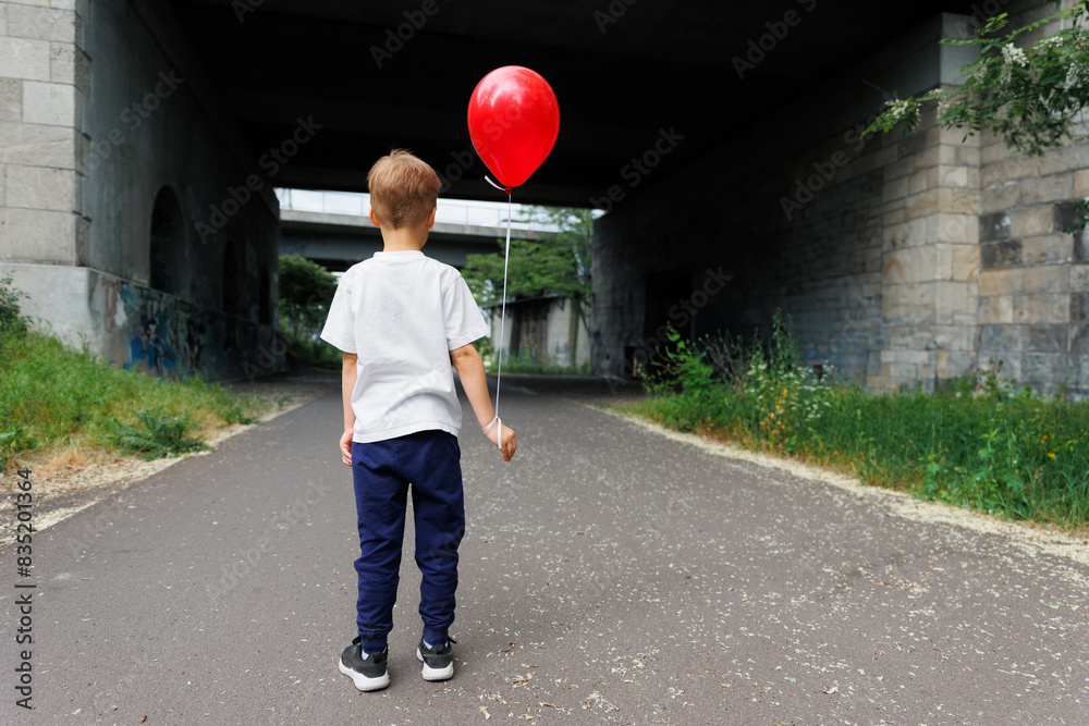 Back view little cute kid boy hold red balloon stand in front of dark ...