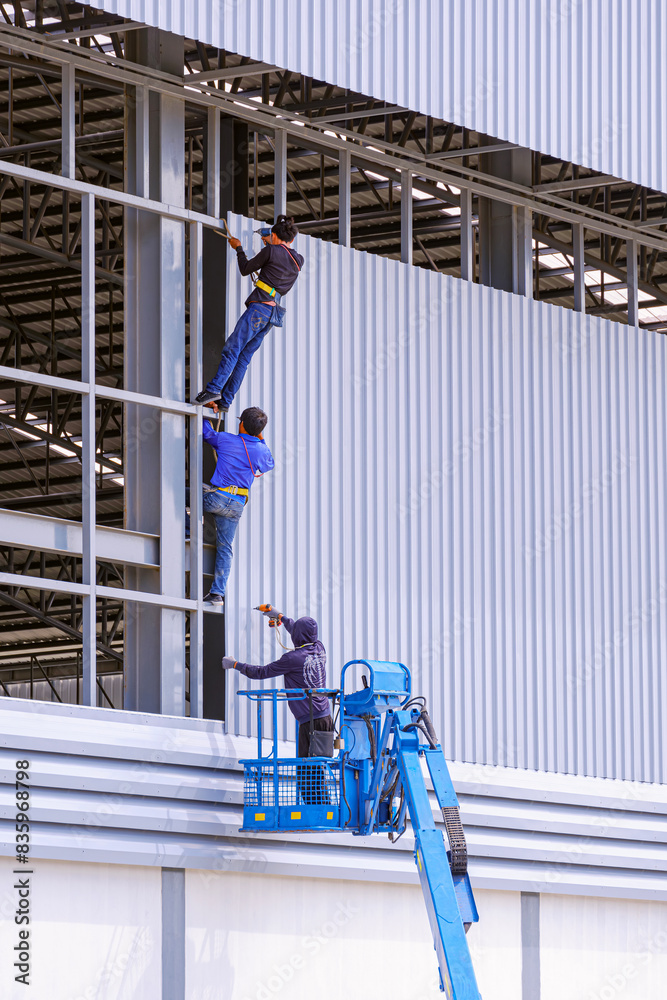 3 construction workers with articulated boom lift installing aluminum ...