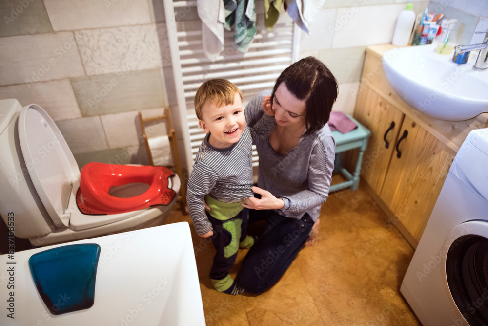 Mom is helping toddler boy use the toilet. Potty-trained little boy in ...