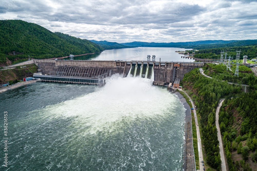 Aerial view of concrete dam releasing water into river on cloudy day ...