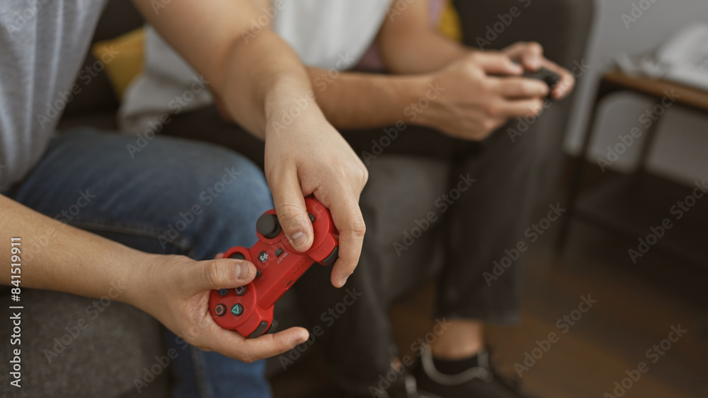Two men enjoying gaming with a red controller indoors, depicting ...