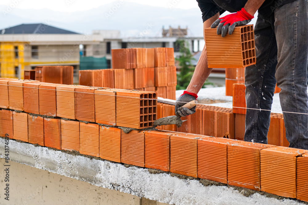Worker builds a brick wall for house construction. Worker building a ...