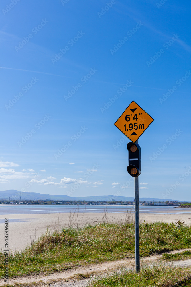 Height limit sign over a traffic warning sign on the beach near some ...