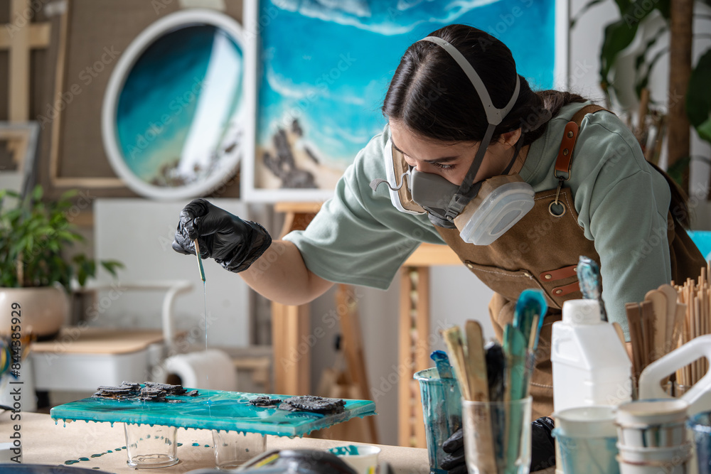 Neat careful female artist dripping epoxy resin on painting. Woman in ...