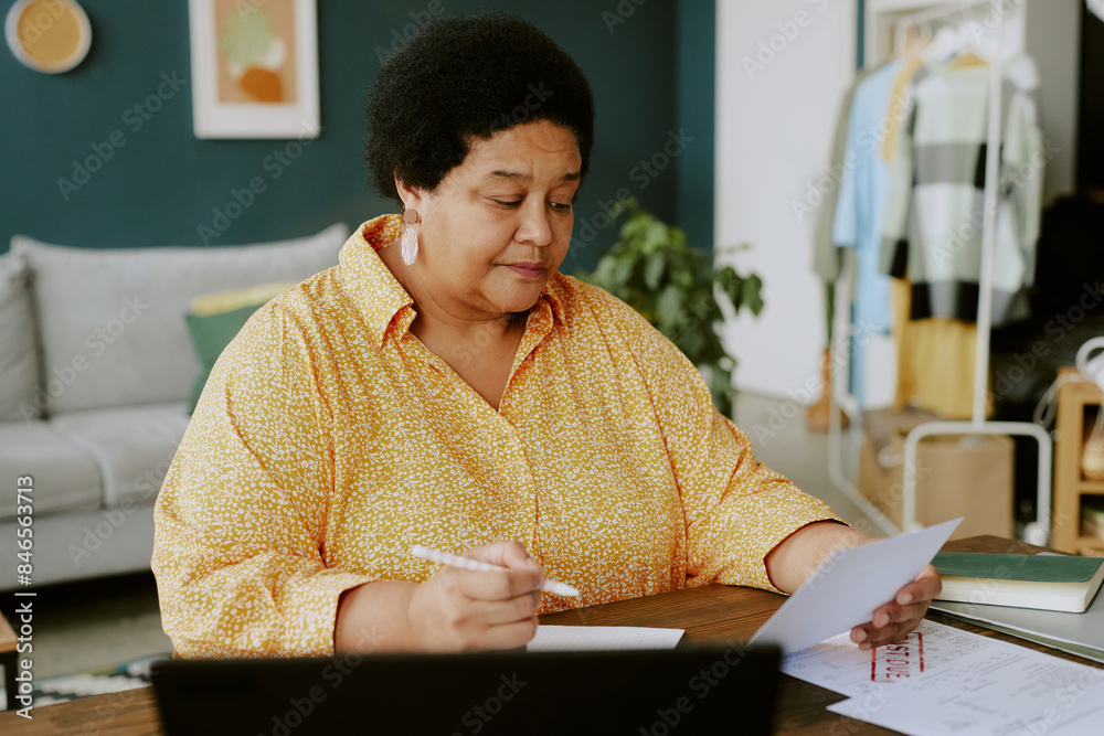 Highly concentrated mature African American woman filling out forms ...