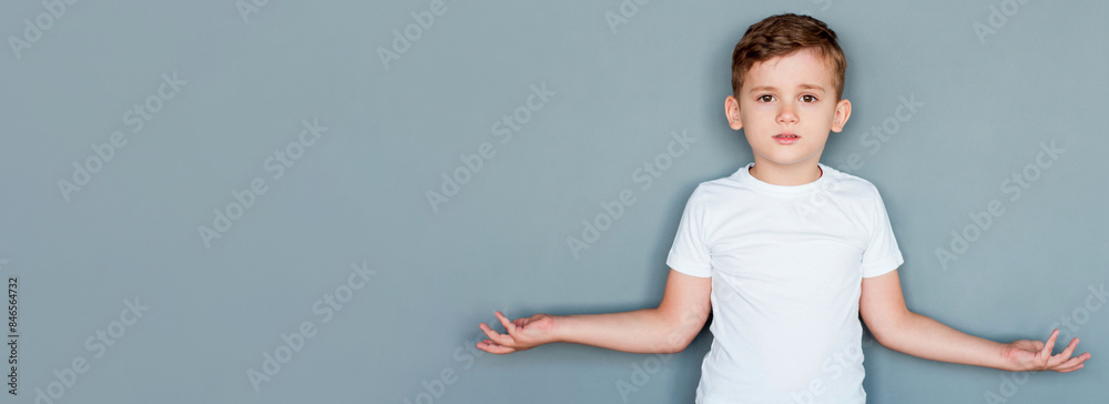 Confused little kid boy wearing basic white t-shirt spreading hands ...