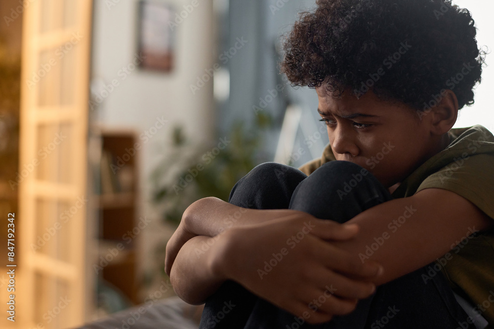 Side view portrait of scared young child crying and hugging knees ...