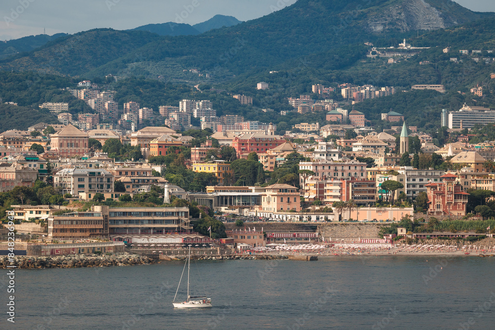 The photo captures a vibrant and bustling scene of Genoa harbor, bathed ...