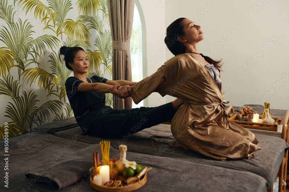 Masseuse pulling arms on client back to open her chest Stock Photo ...