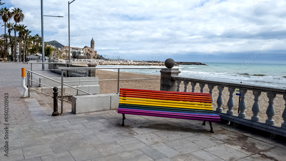 Colorful seaside promenade with a vibrant, rainbow-painted bench, palm ...