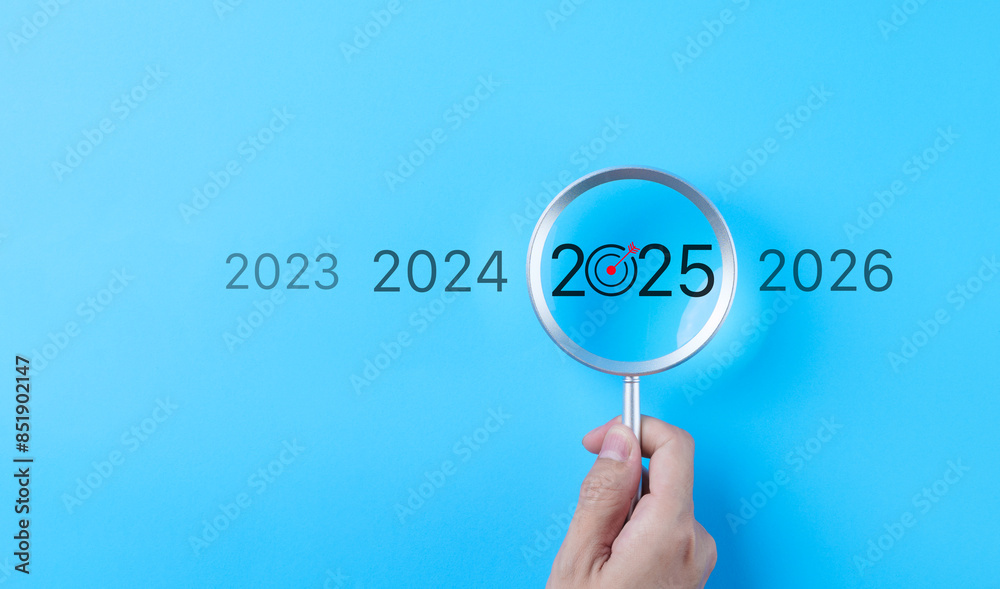 The 2025 New Year business goals concept. Hand holding a magnifying ...