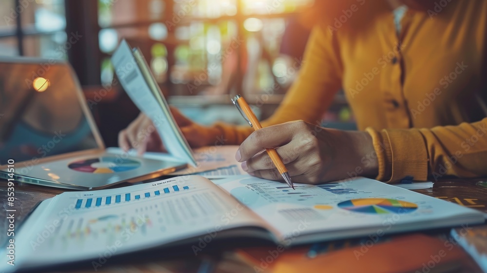 A hand turning a page of a financial plan book with charts and graphs ...