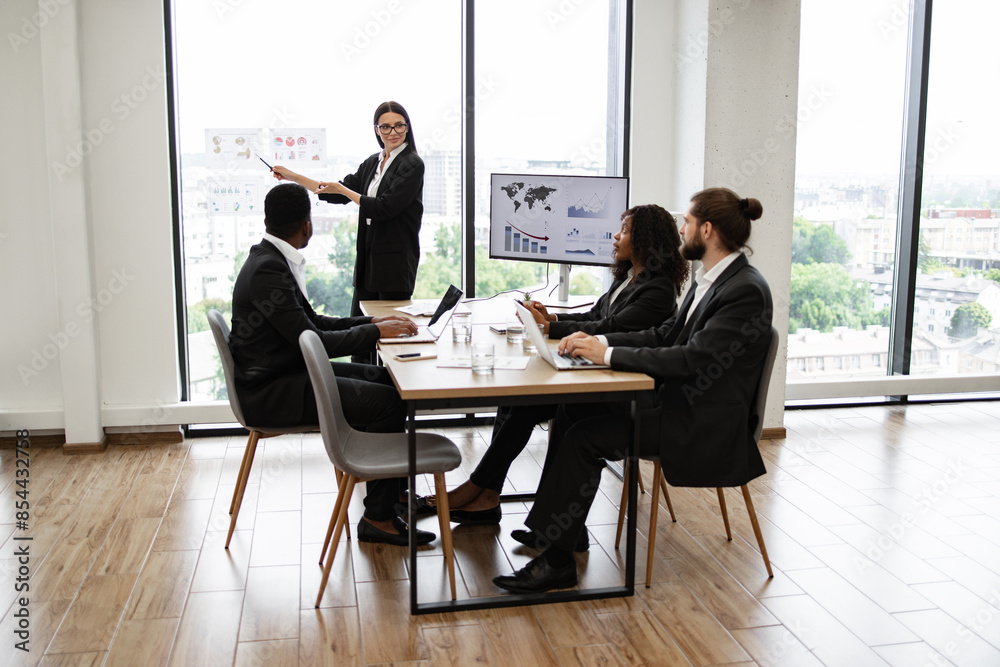 Business team in formal attire engaging in presentation with charts and ...
