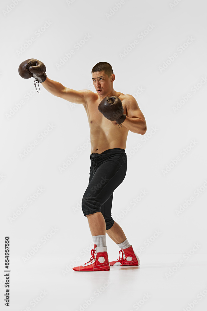 Focused and concentrated shirtless young man in brown old style boxing ...
