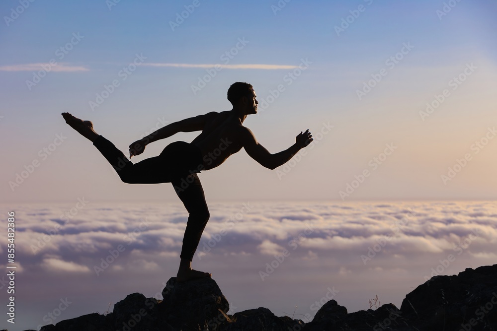 Silhouette of male ballet dancer posing a majestic dance move on rocks ...
