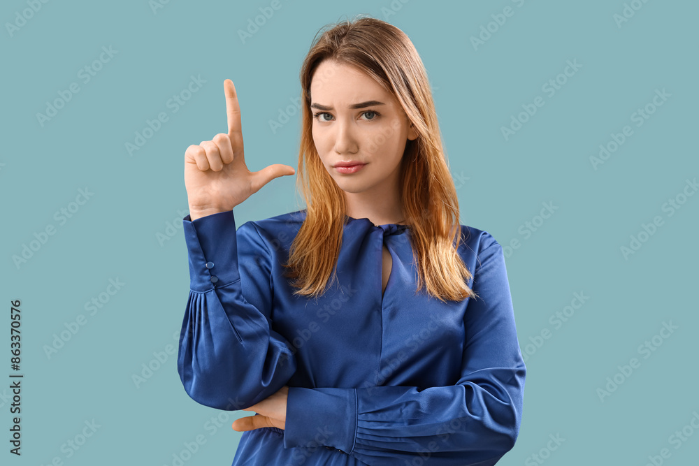Upset young woman showing loser gesture on blue background Stock Photo ...