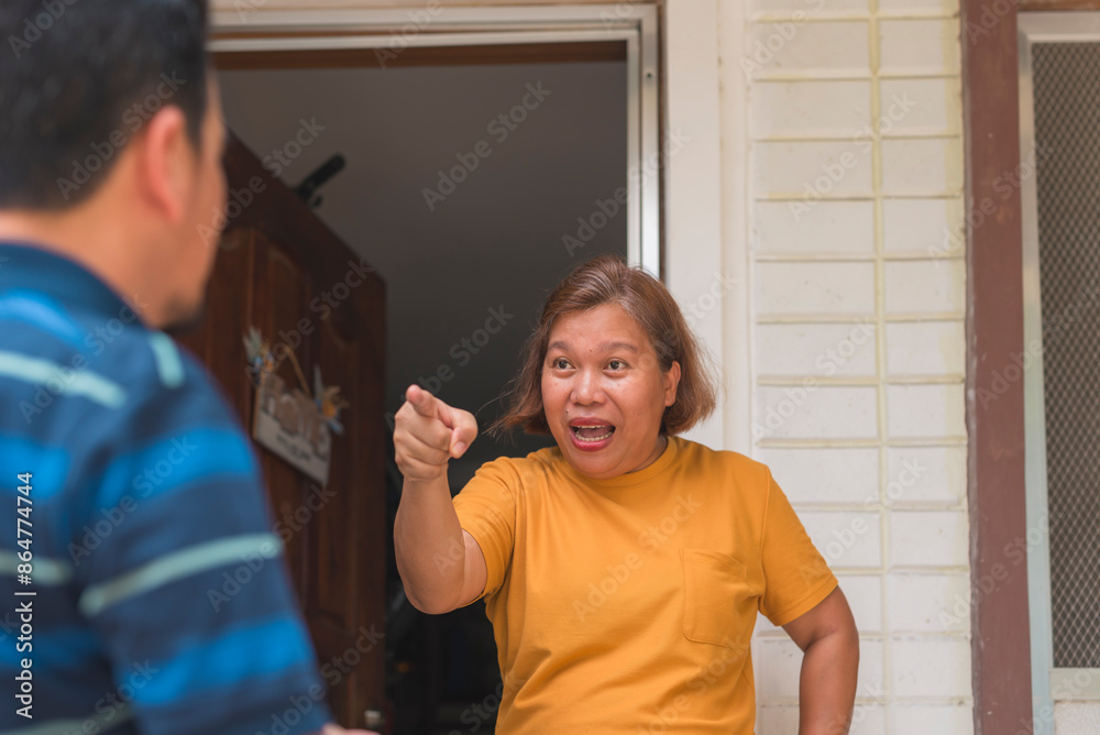 An upset woman pointing and scolding her husband in front of their ...