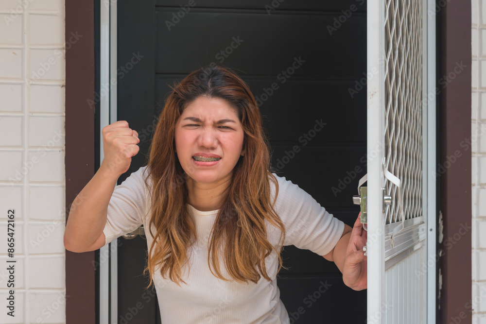 An angry asian woman in her 30s stands just outside her apartment flat ...