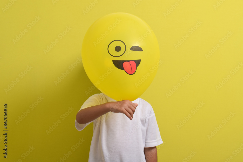 Tongue emoji. Cute Asian boy hiding his face behind balloon emoticon ...