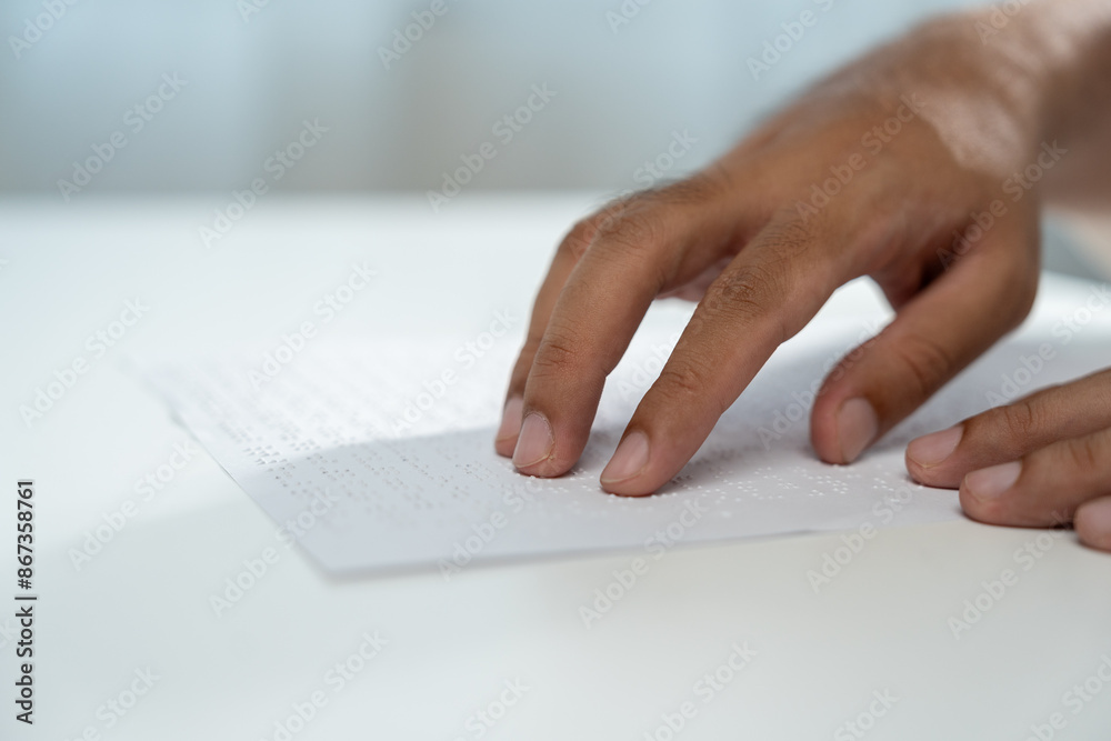Hand of a blind person reading some braille text on page paper to learn ...