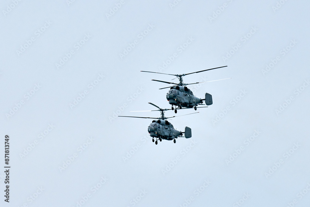 Two Russian military helicopters armed with missiles flies in blue sky ...