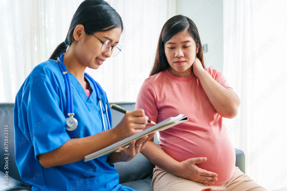 Asian female doctor and nurse consult on sofa with a pregnant woman ...