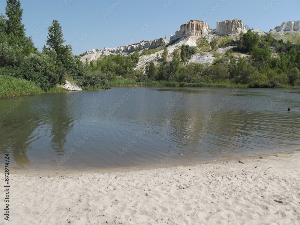 Limestone cliffs and a lake with smooth water surface in an old disused ...