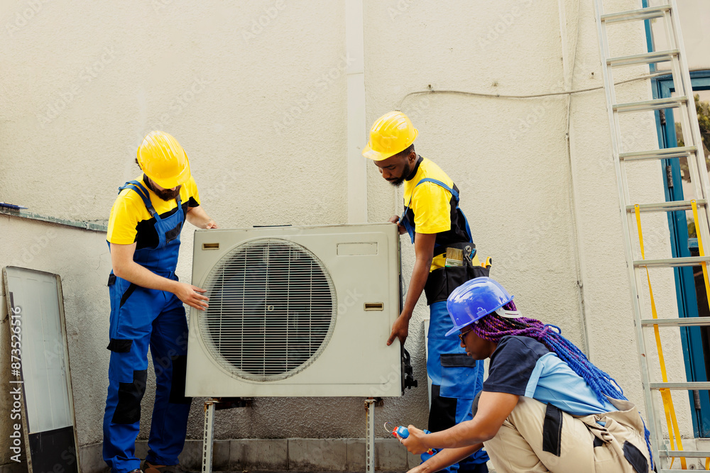 Proficient workers putting new external air conditioner in place for ...