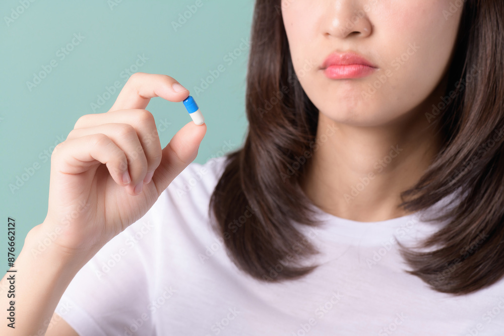 Forget taking medicine. Confused woman holds head and looks at pills on ...