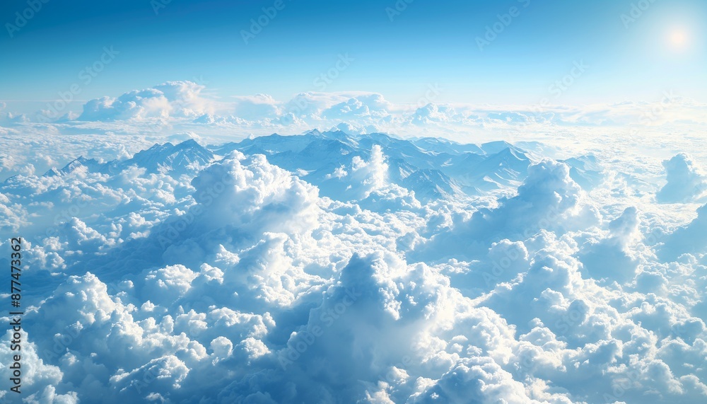 An aerial view of fluffy clouds hovering over a vast expanse of rugged ...
