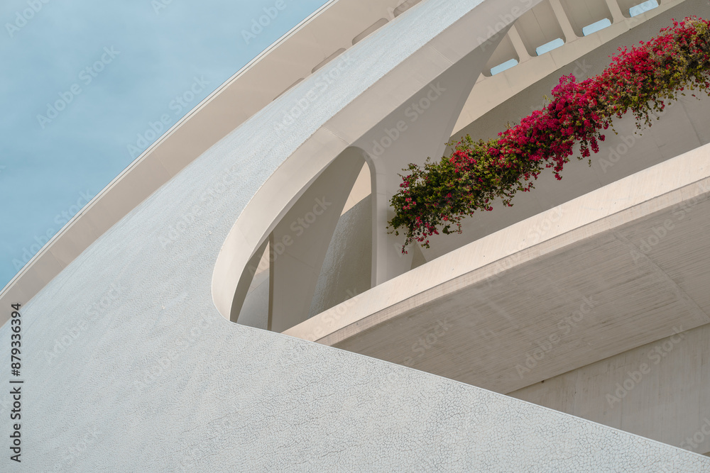 A modern curved building with a floral accent on the balcony. The ...