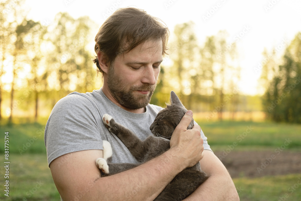 Adult Man holding in hand his cat outdoors. Handsome guy holding cat ...