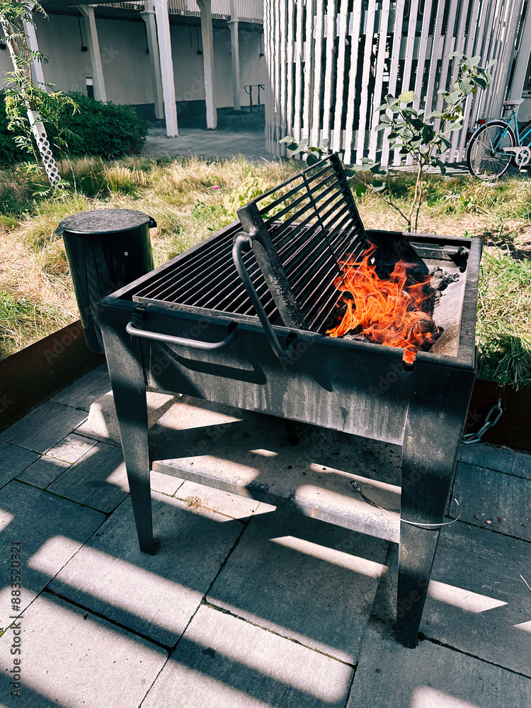 Firewood burns in an open grill in the yard against the backdrop of a ...