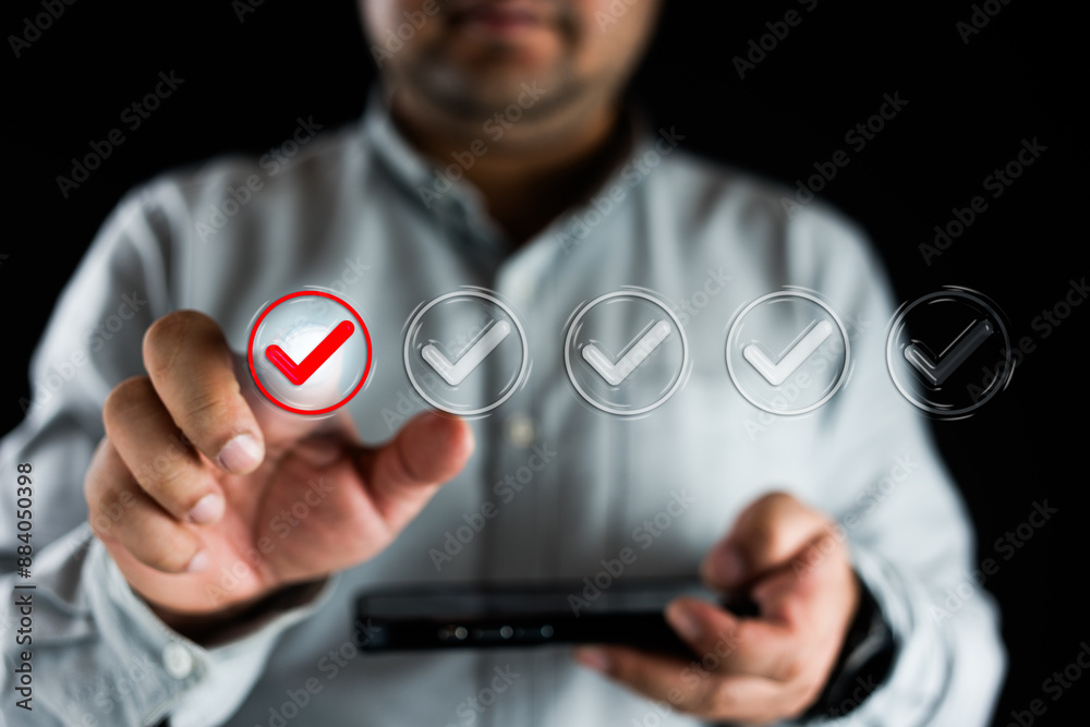 Businessman checking mark on the checklist with a red marker on dark ...