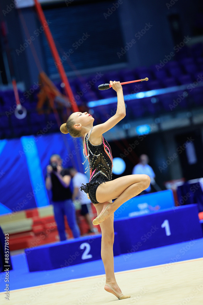 A gymnast with clubs shows talent, flexibility, and grace at a rhythmic ...