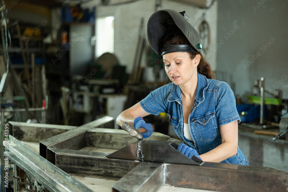 Portrait of a female welder standing with a welding semi-automatic ...