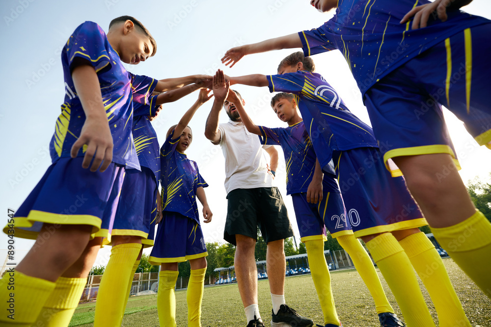 Kids and coach demonstrate team unity, putting their hands together in ...