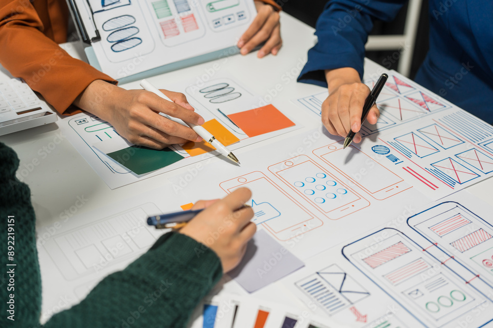 A group of people collaborates around a desk, discussing and reviewing ...