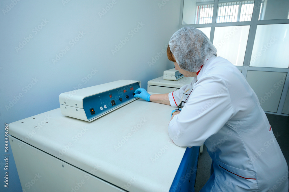Lab assistant working with control panel of centrifuge to separate ...