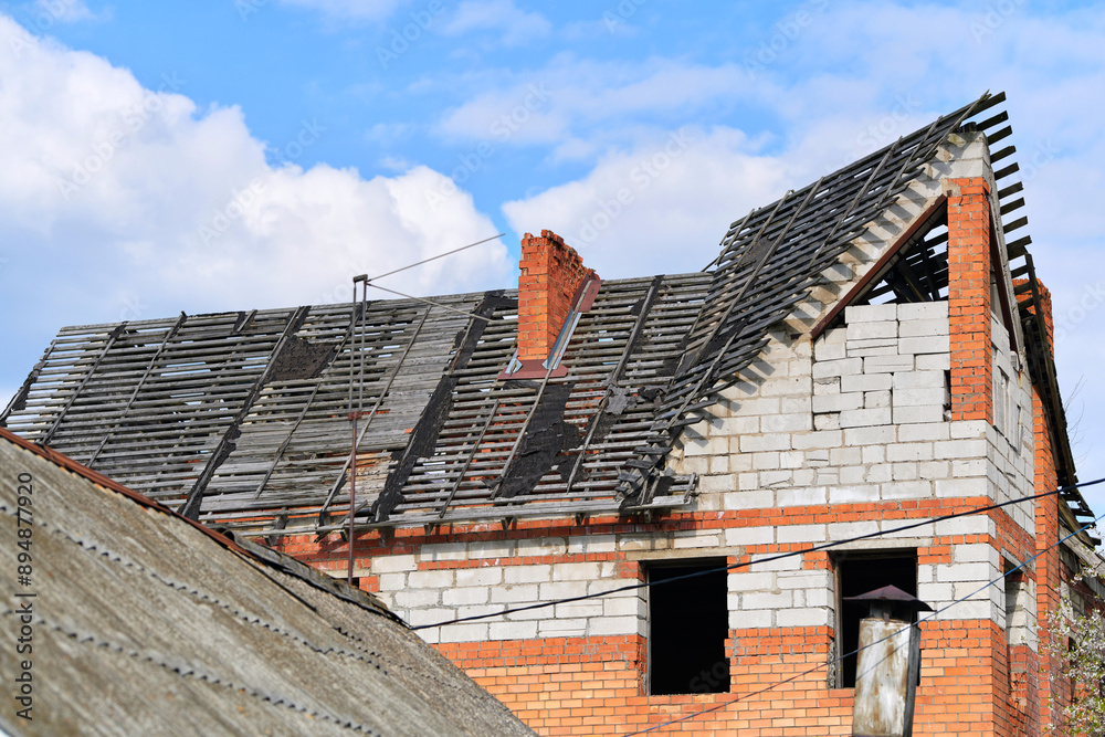 House with broken roof, fire damage. Dilapidated brickwork, derelict residential building with ...