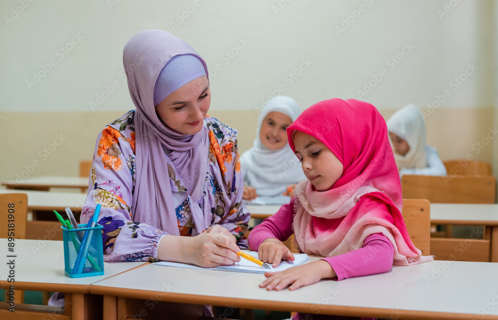 Female hijab Muslim teacher helps school kid to finish the lesson ...